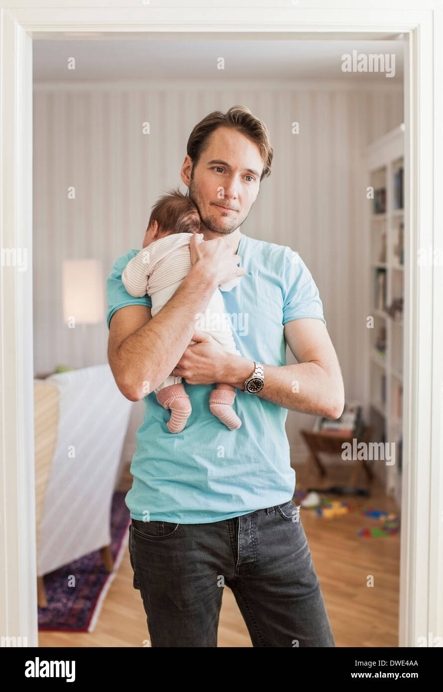 Thoughtful man carrying baby at doorway Stock Photo - Alamy