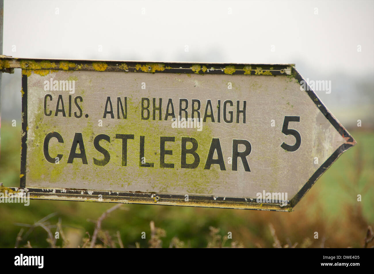 An old moss covered sign marking five miles to the town of Castlebar ...