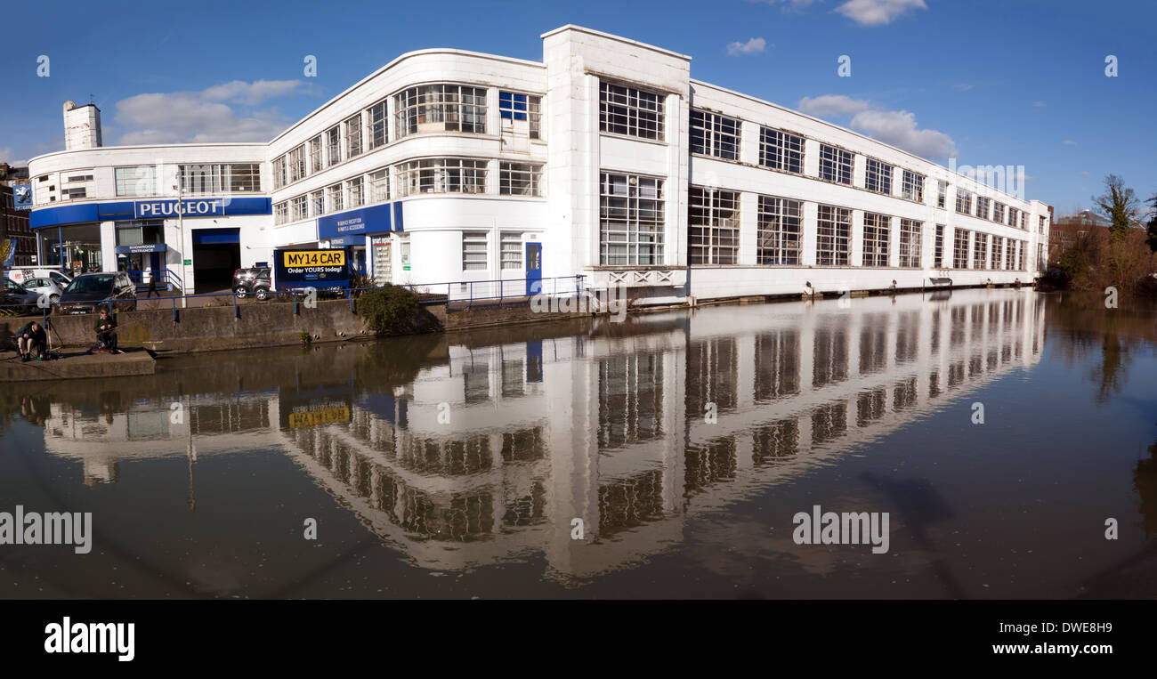 An Art Deco 1930's style building, reflected in an old millpond on the ...