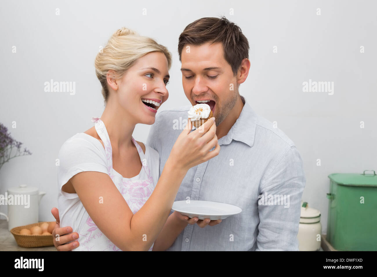 Happy woman feeding man pastry in kitchen Stock Photo - Alamy