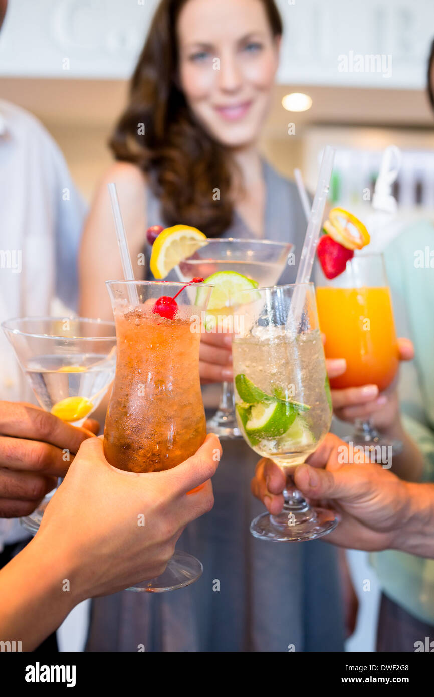 Closeup of cheerful people toasting cocktails over blurred background ...