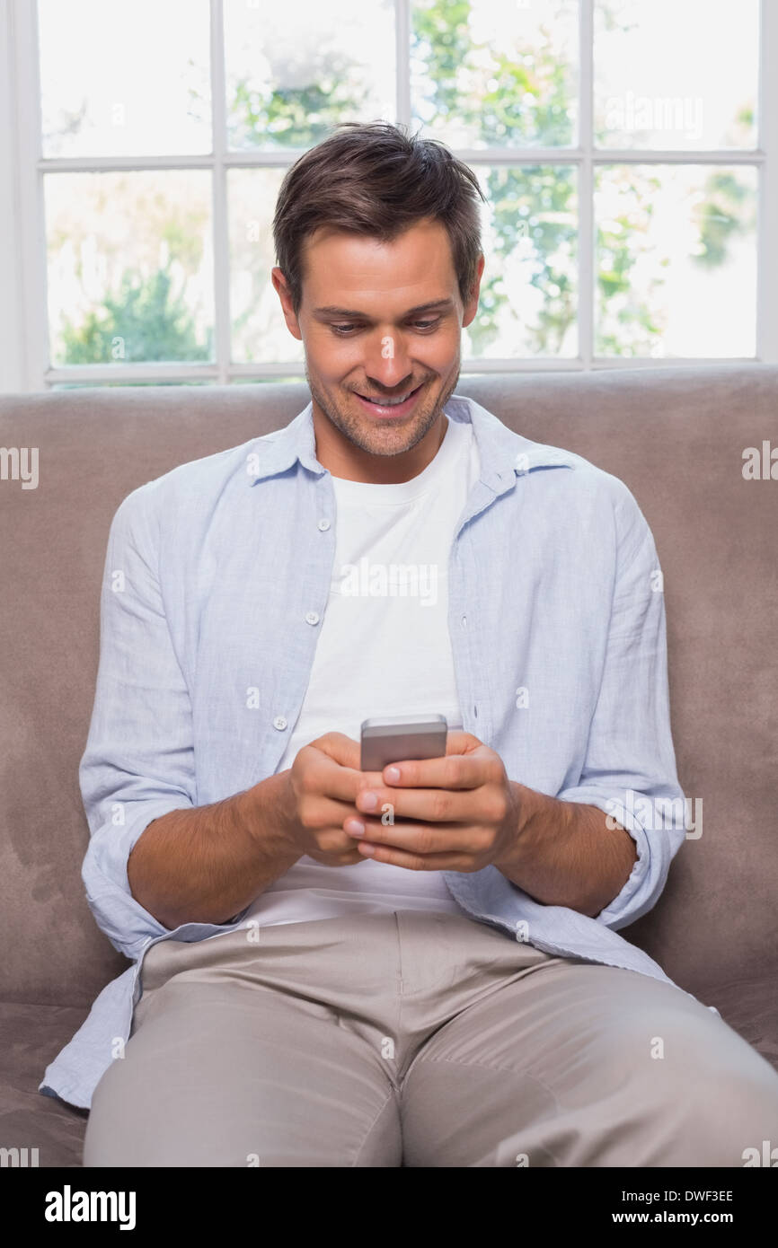 Casual man reading text message on sofa Stock Photo - Alamy