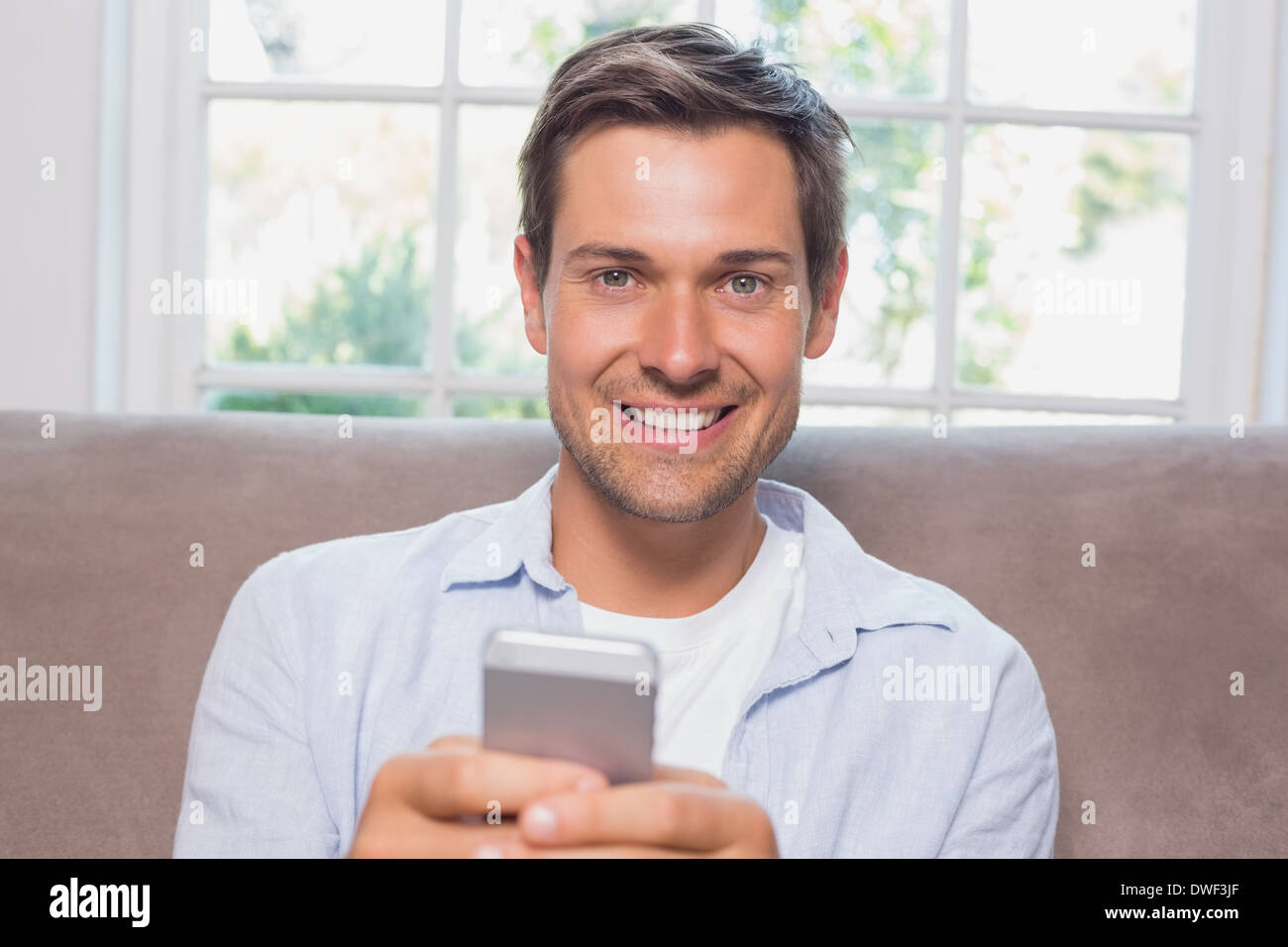 Portrait of a casual man reading text message on sofa Stock Photo - Alamy