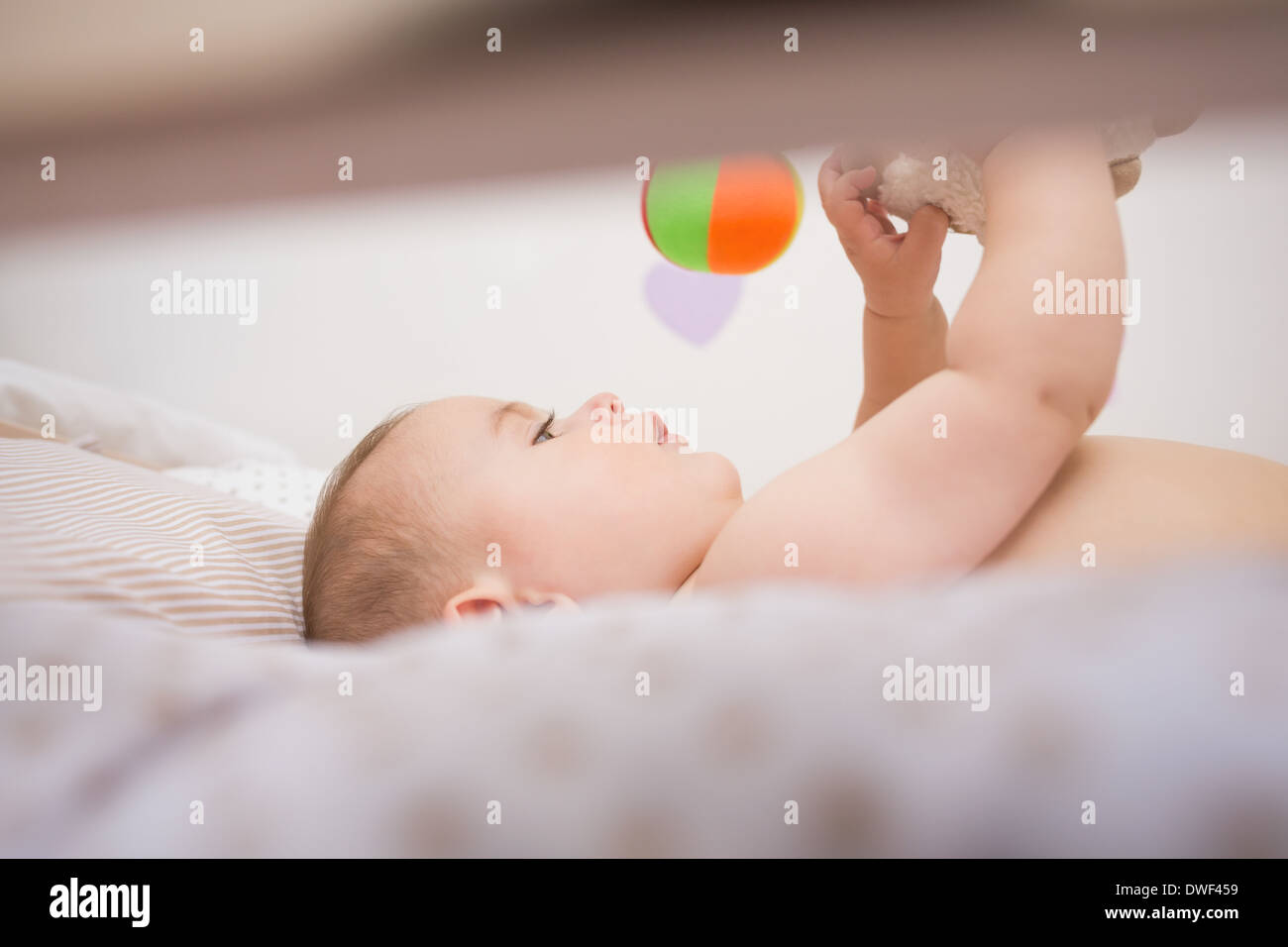 Baby lying on back holding toy hi-res stock photography and images - Alamy
