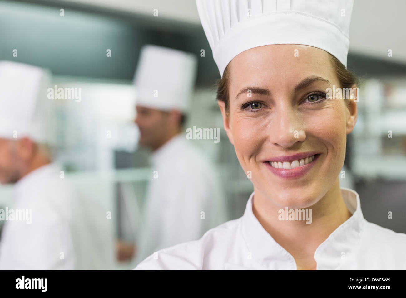 Smiling chef looking at camera with team working behind Stock Photo - Alamy