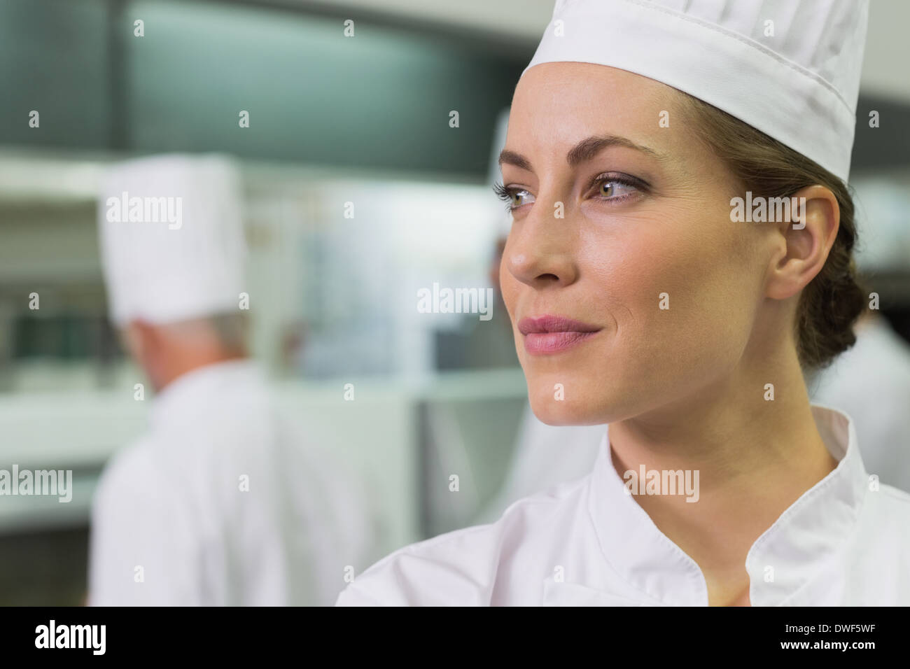 Serious chef looking away with team working behind Stock Photo - Alamy