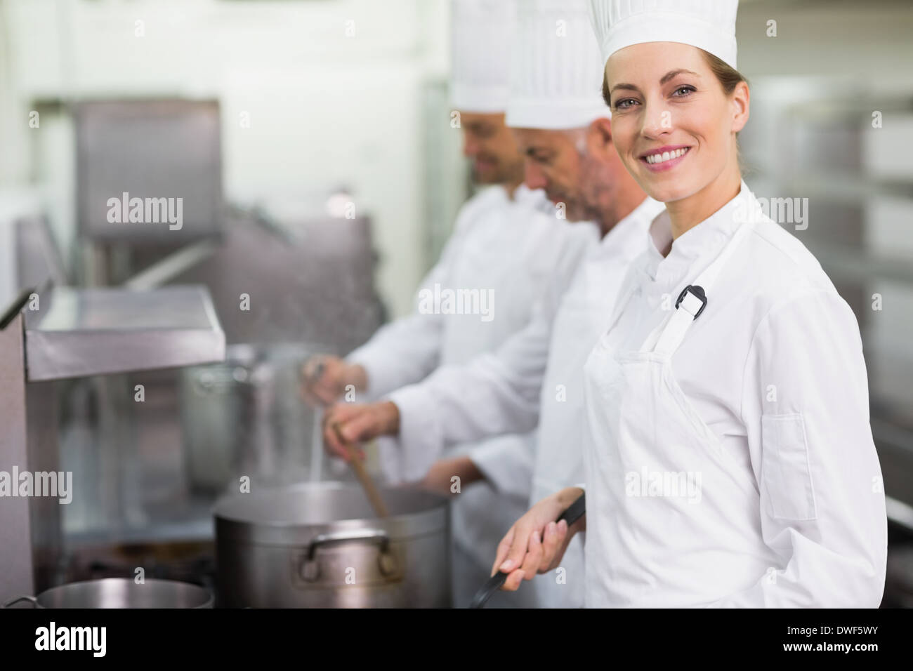 Happy chef smiling at camera while cooking at stove Stock Photo - Alamy