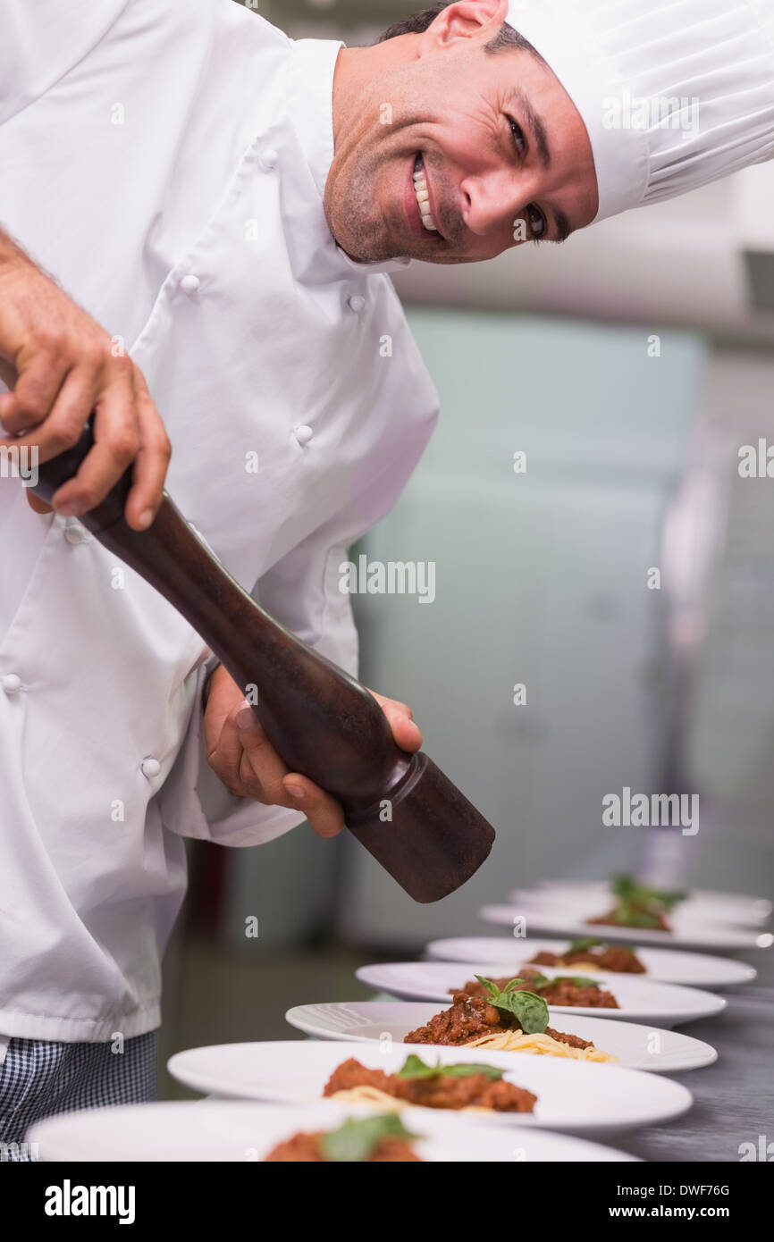 Happy chef grinding pepper over spaghetti dish Stock Photo - Alamy