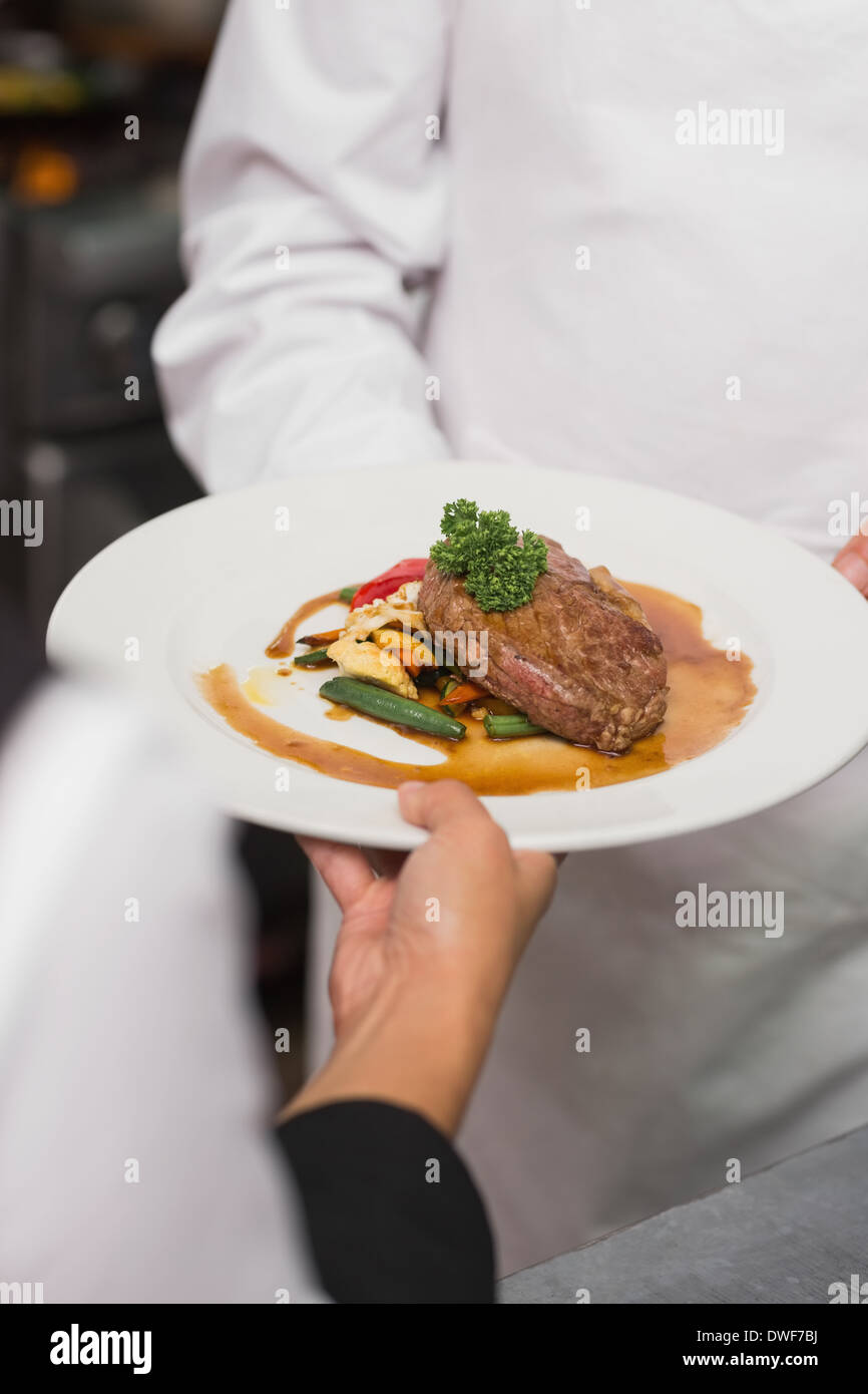 Waitress taking steak dinner from chef Stock Photo - Alamy