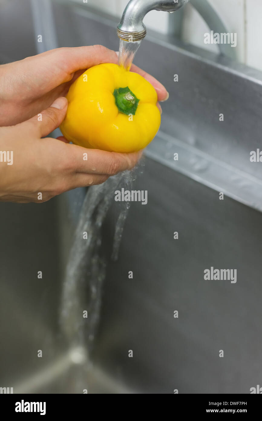 Chef washing pepper under the tap in a commercial kitchen Stock Photo ...