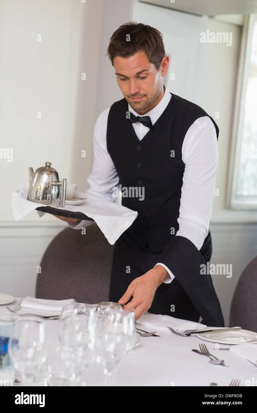 Waiter holding tray and setting table Stock Photo - Alamy