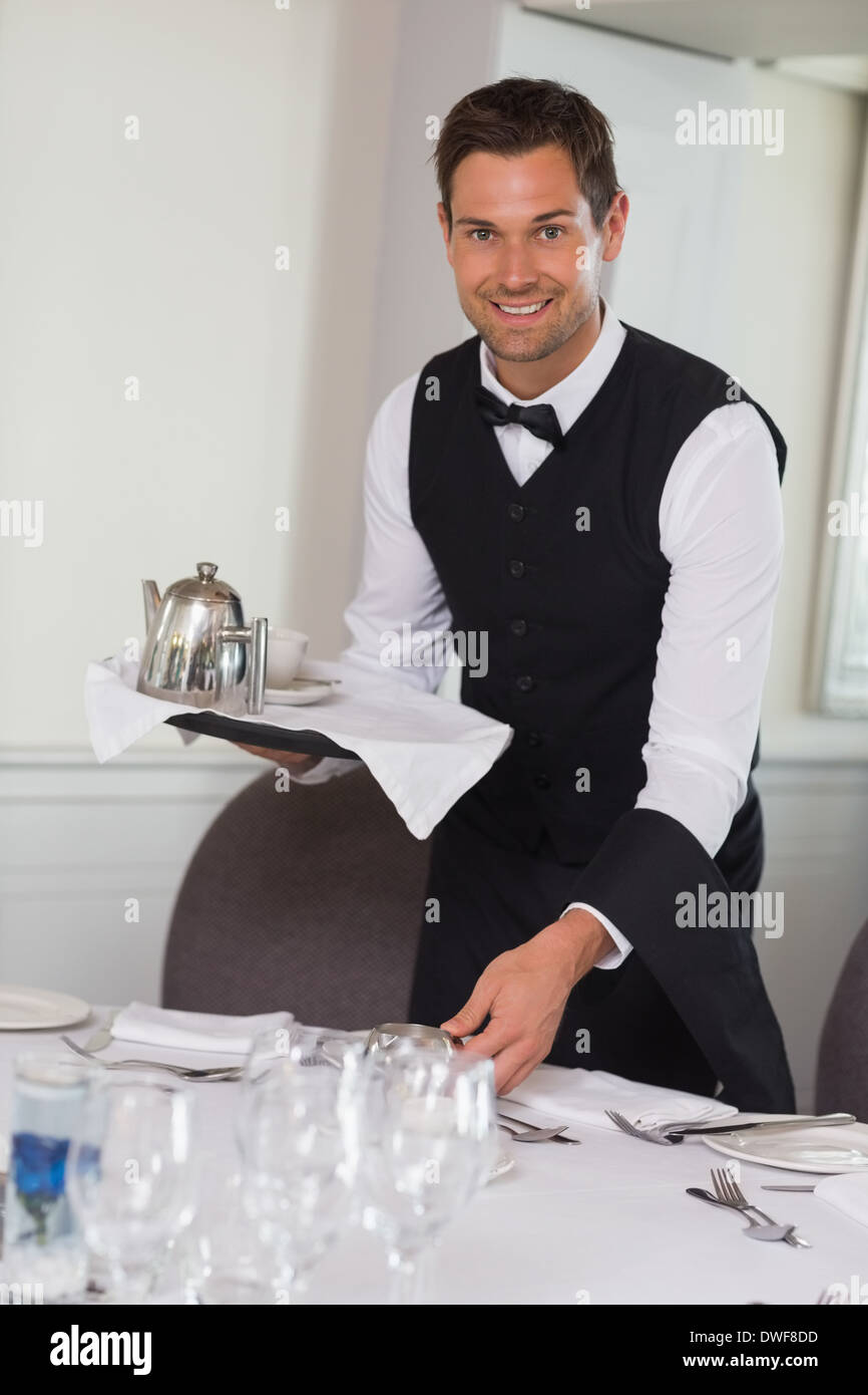 Happy waiter holding tray and setting table Stock Photo - Alamy