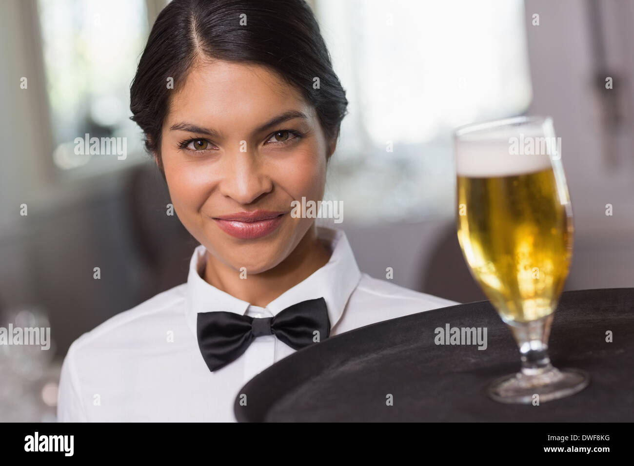 Pretty waitress holding tray with glass of beer Stock Photo - Alamy