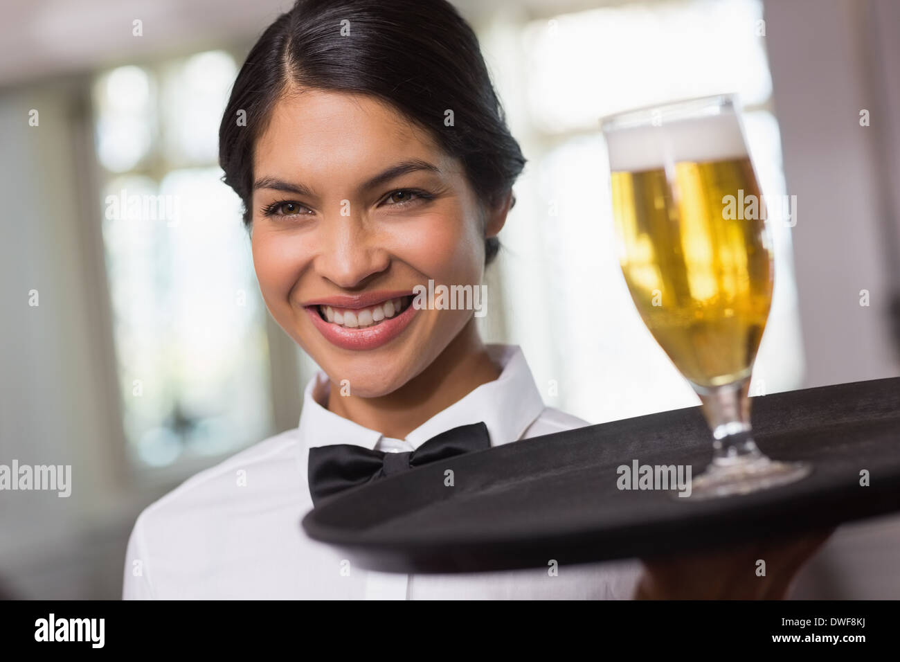 Pretty waitress holding tray with glass of beer Stock Photo - Alamy