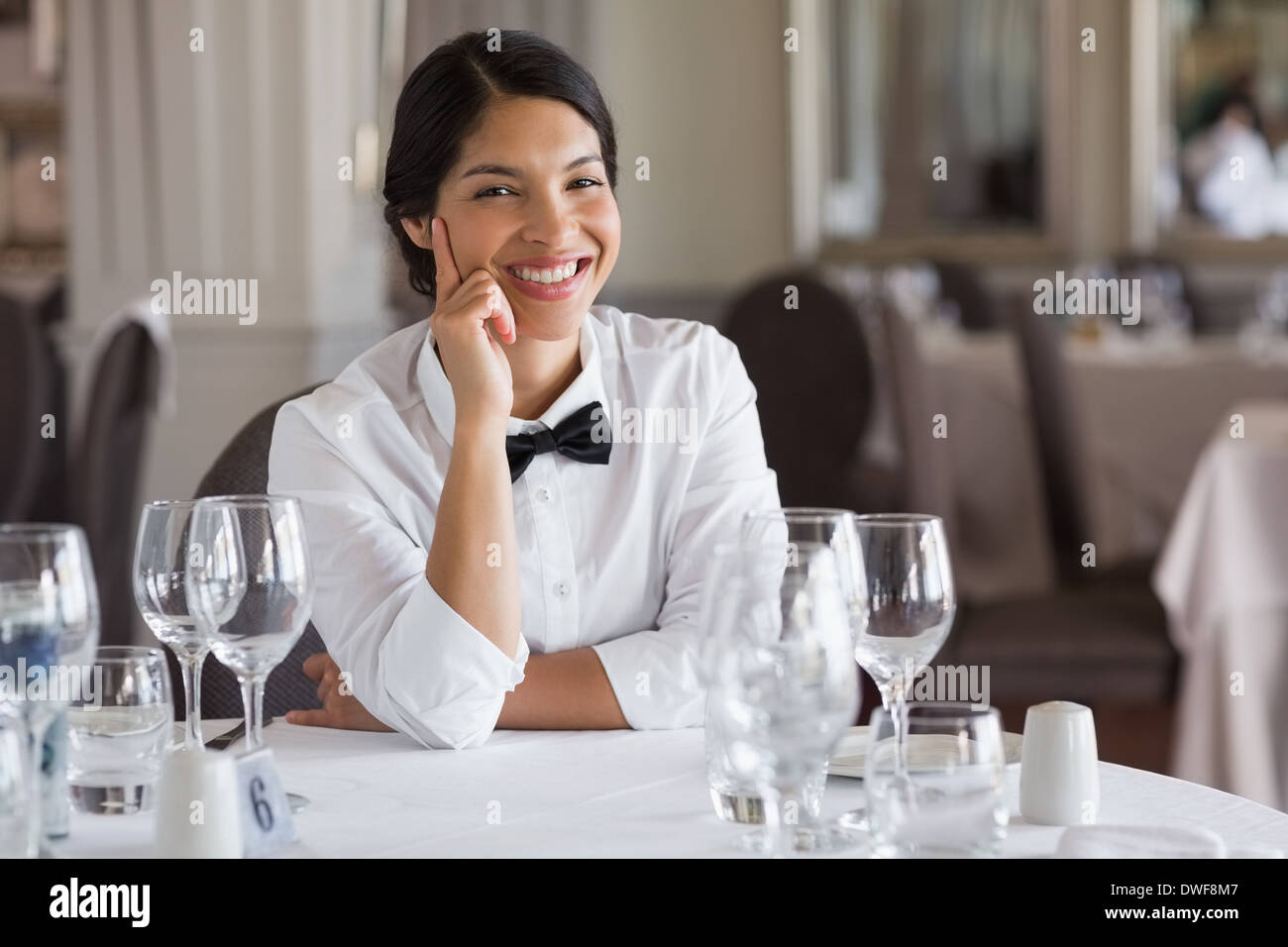 Pretty waitress sitting at set table Stock Photo - Alamy