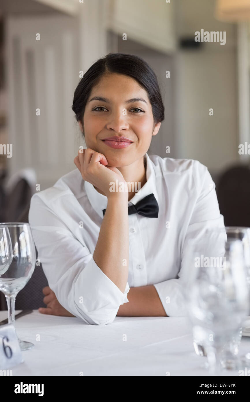 Happy waitress sitting at set table Stock Photo - Alamy