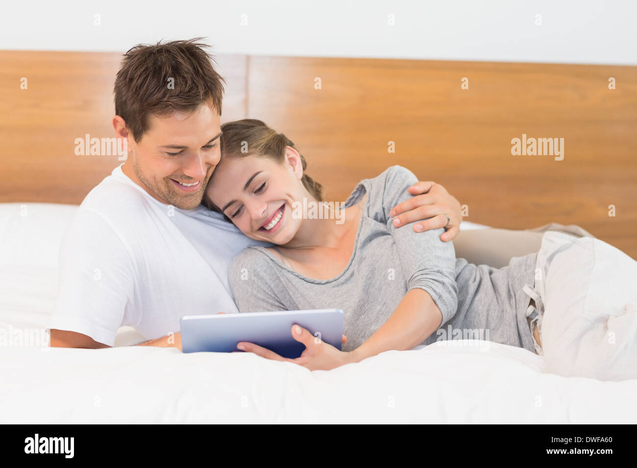 Happy couple on bed using tablet pc Stock Photo - Alamy