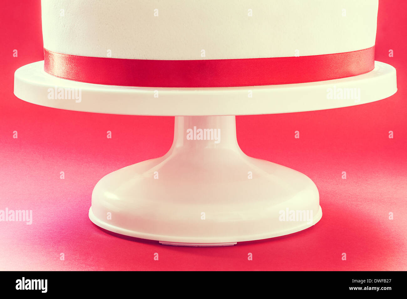White round cake on red background, decorated with red ribbon Stock ...
