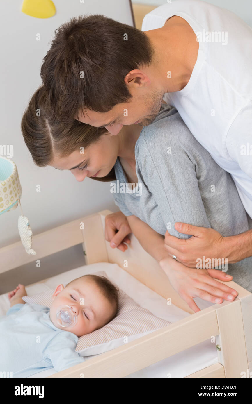 Happy parents watching over baby son in crib Stock Photo - Alamy
