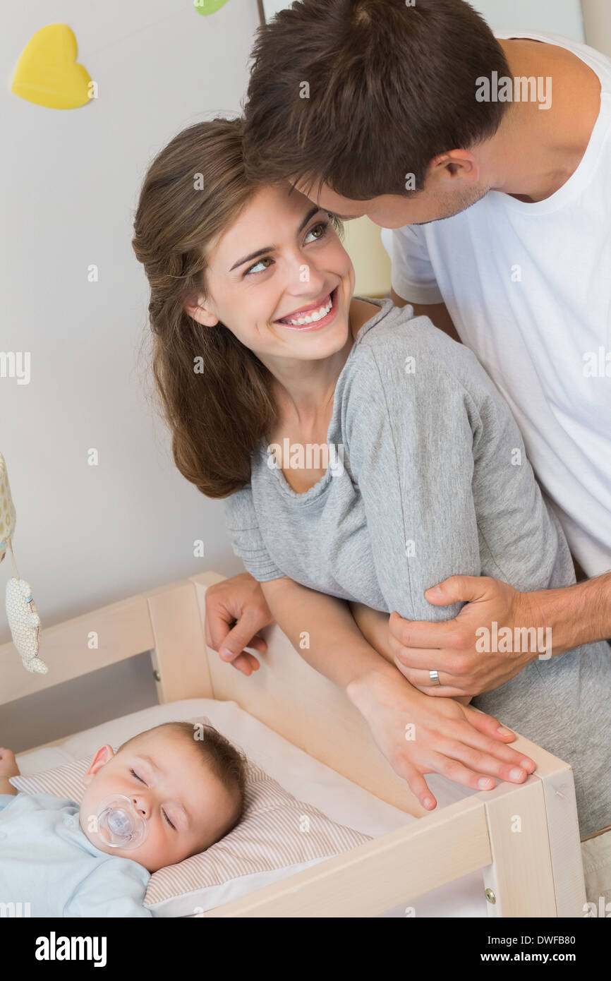 Happy parents watching over baby son in crib at home in bedroom Stock ...