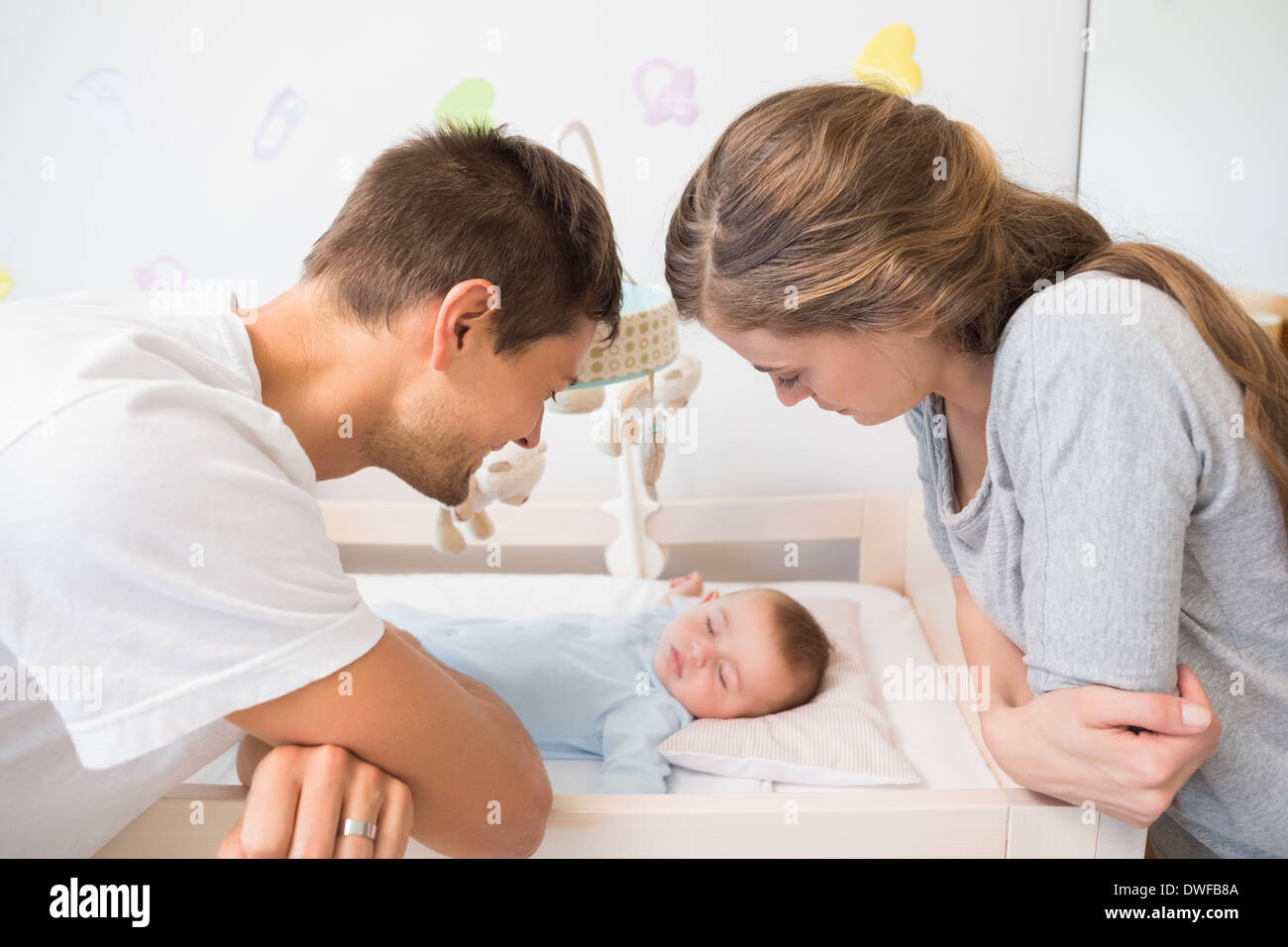 Happy parents watching over baby son in crib Stock Photo - Alamy