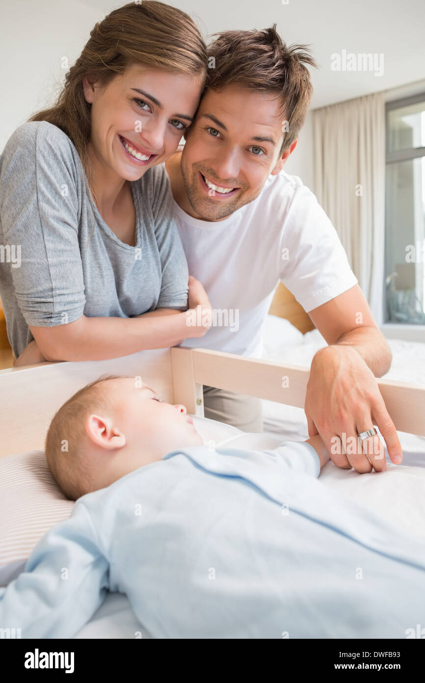 Happy parents watching over baby son in crib Stock Photo - Alamy