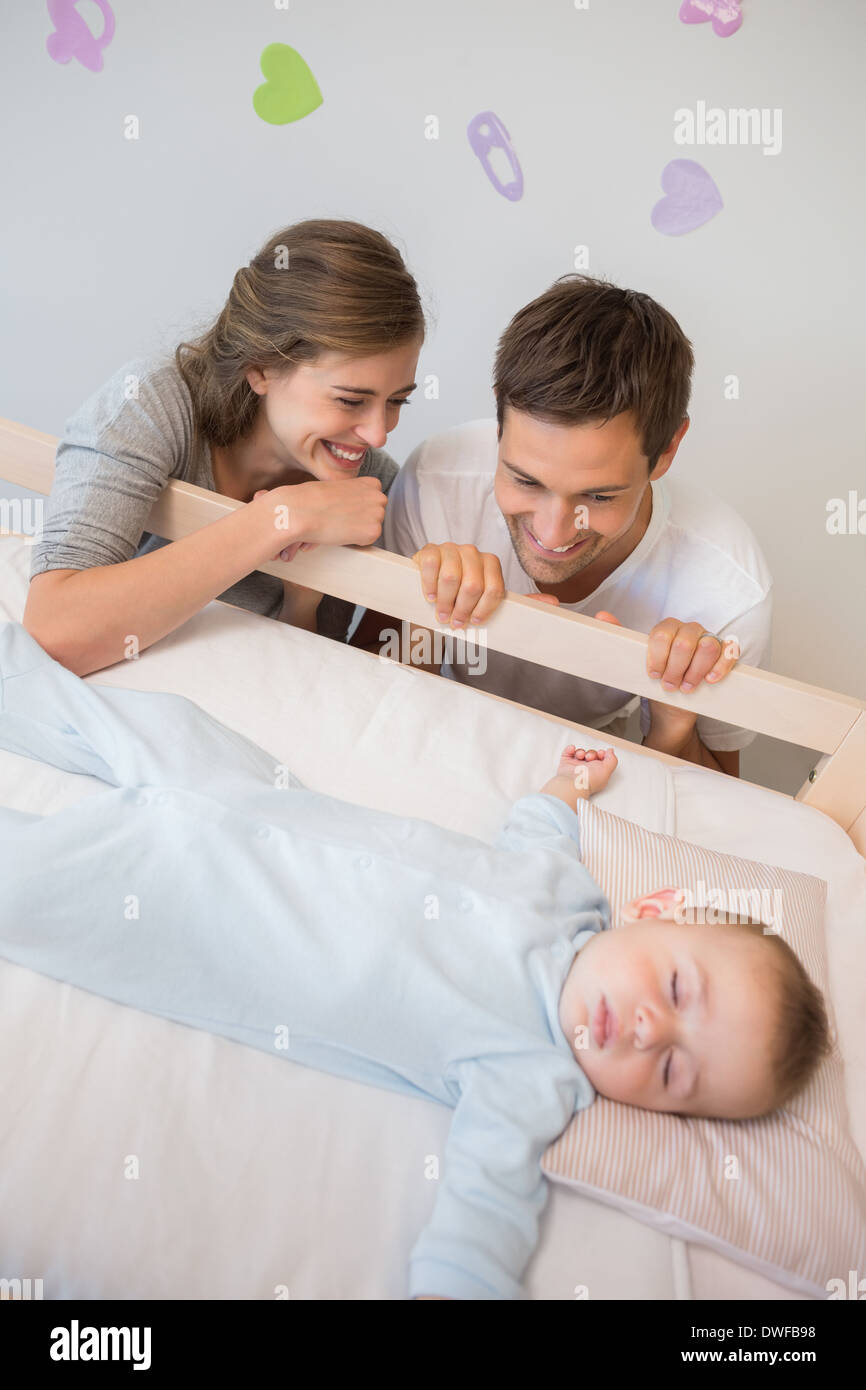 Happy parents watching over baby son in crib Stock Photo - Alamy