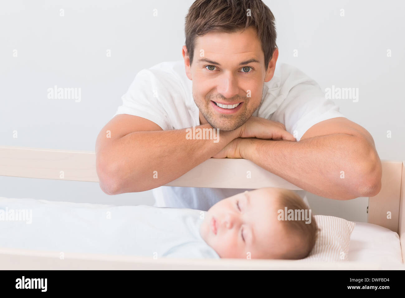 Happy father watching over baby son in crib Stock Photo - Alamy