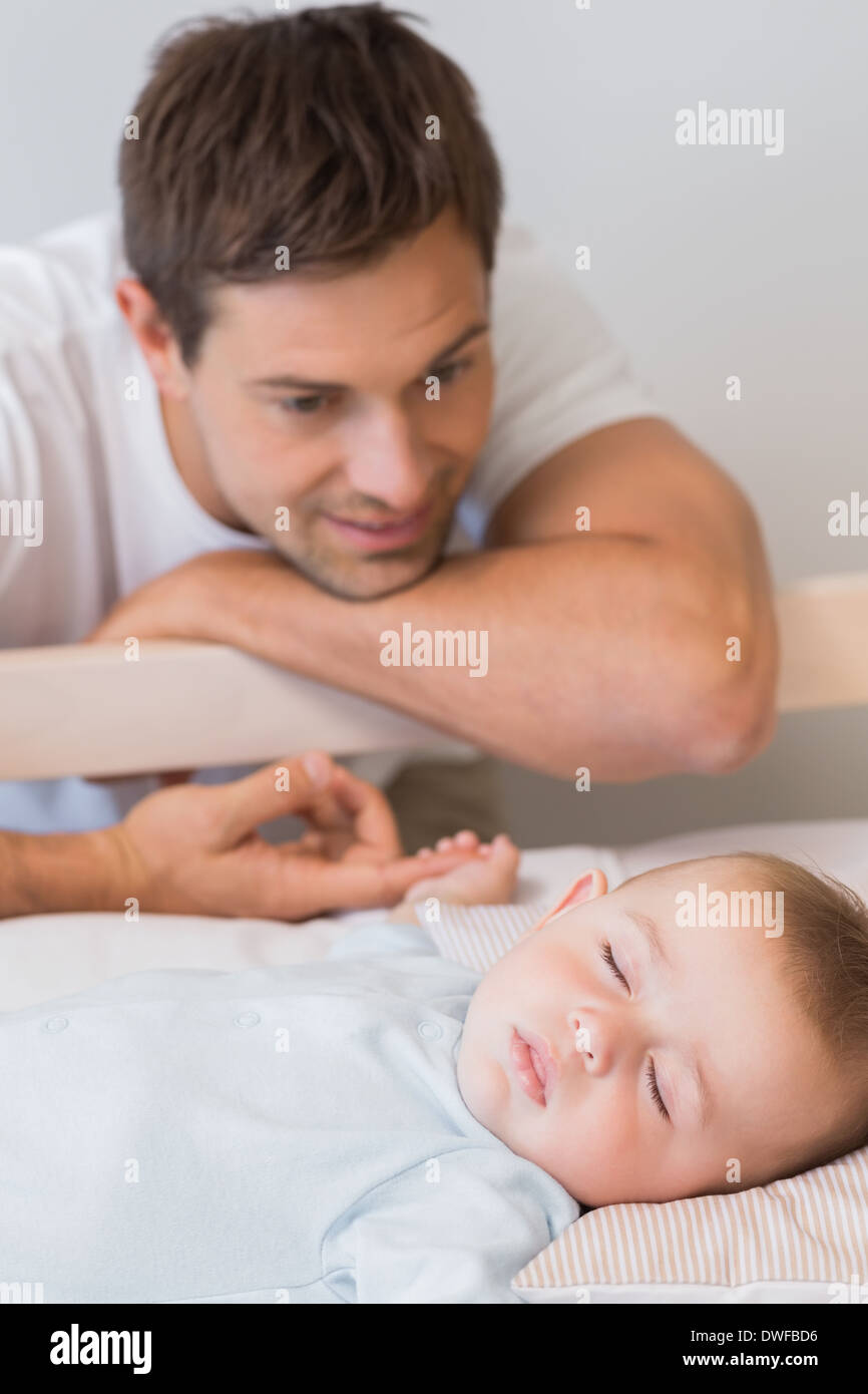 Happy father watching over baby son in crib Stock Photo - Alamy