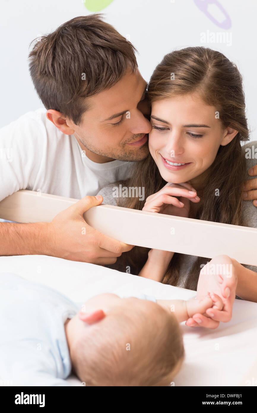 Happy parents watching over baby son sleeping in crib Stock Photo - Alamy