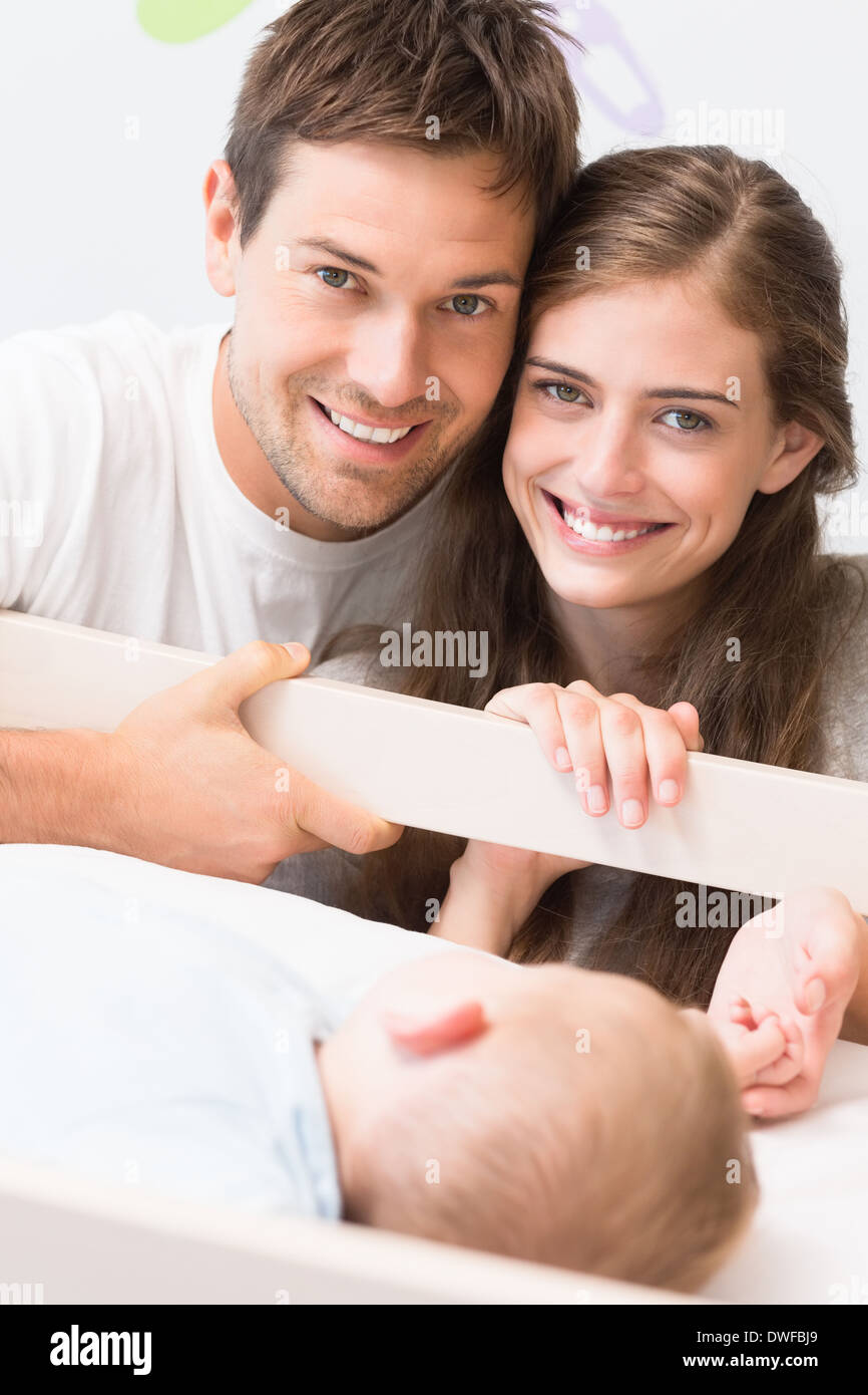 Happy parents watching over baby son sleeping in crib Stock Photo - Alamy