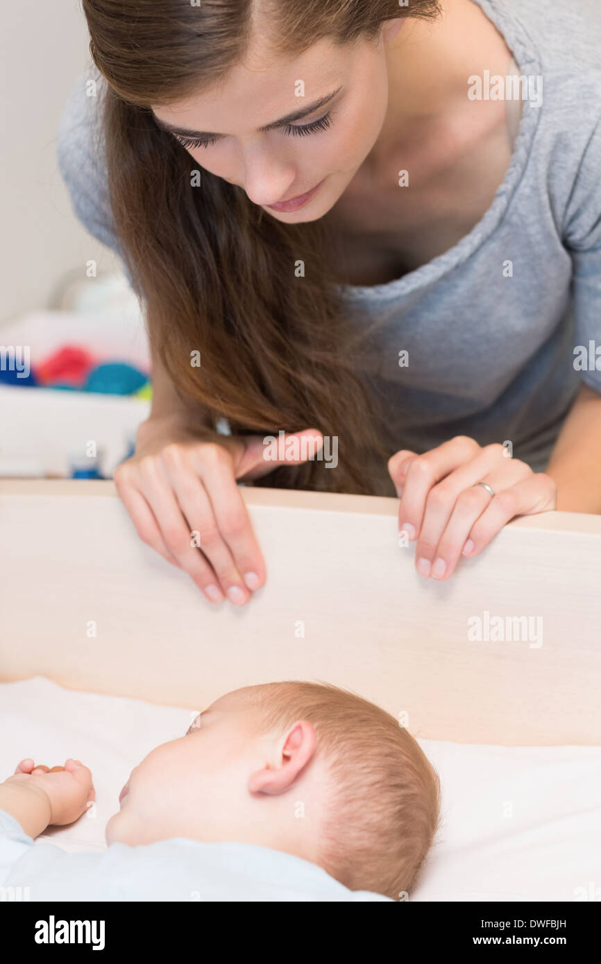Happy mother watching over baby son sleeping in crib Stock Photo - Alamy