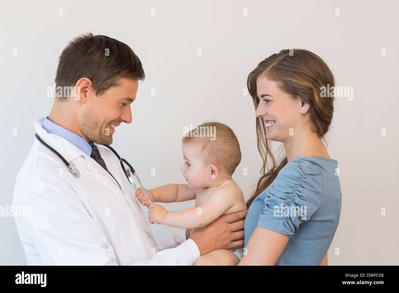 Handsome pediatrician checking baby boy held by his mother Stock Photo ...
