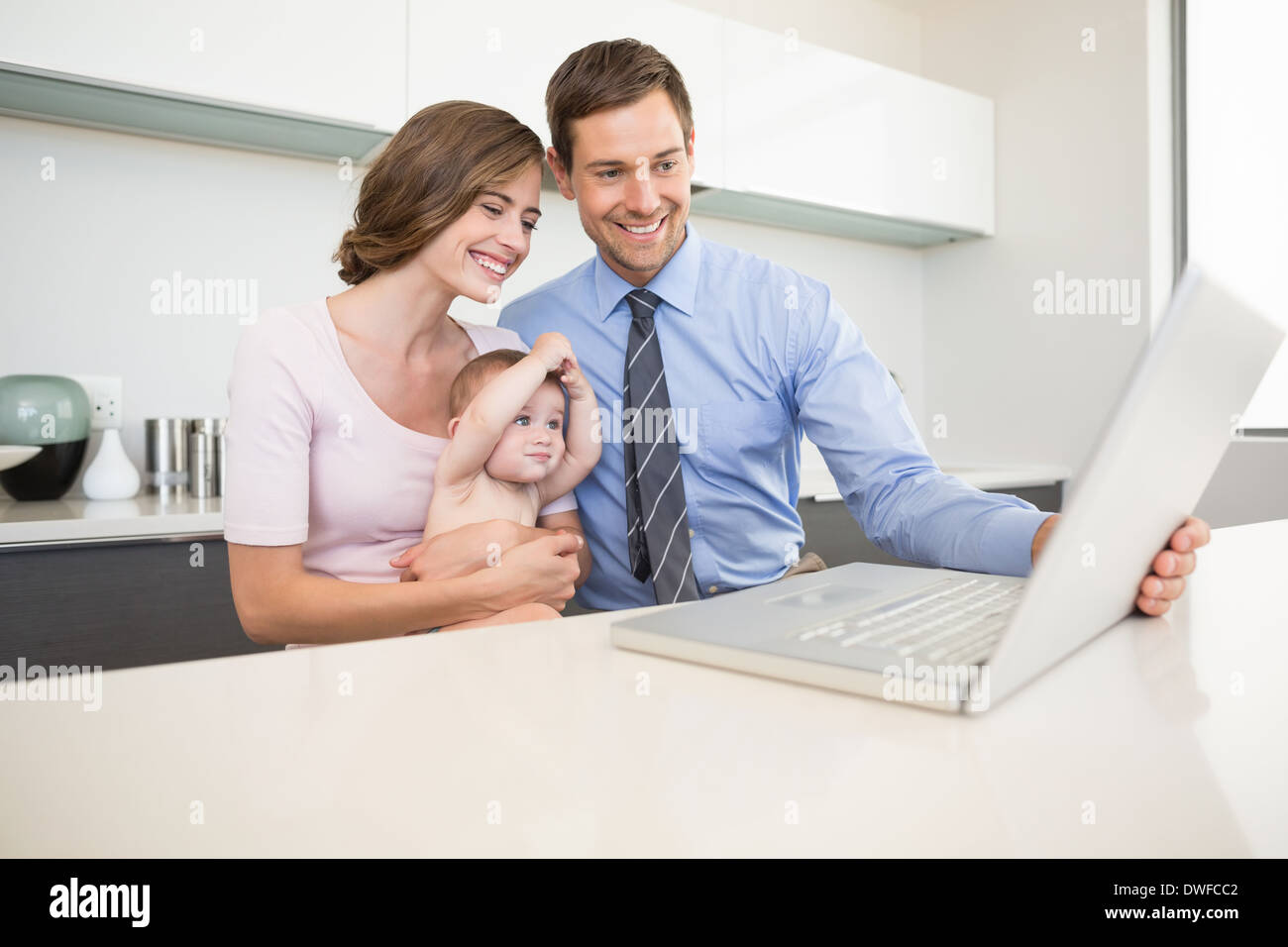 Parents using the laptop with their baby son at counter Stock Photo - Alamy