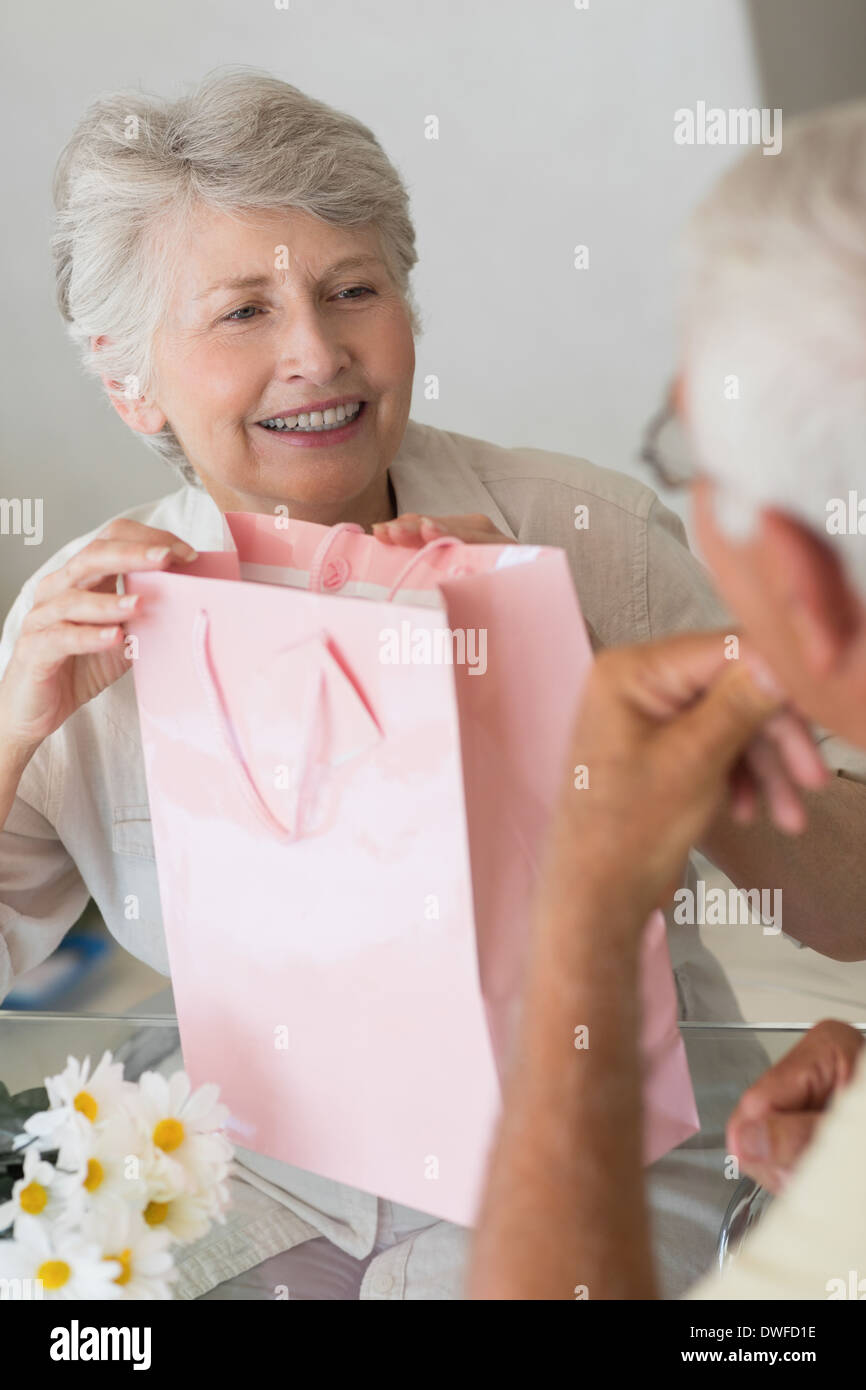 Happy senior woman getting a gift from her partner at home in the ...