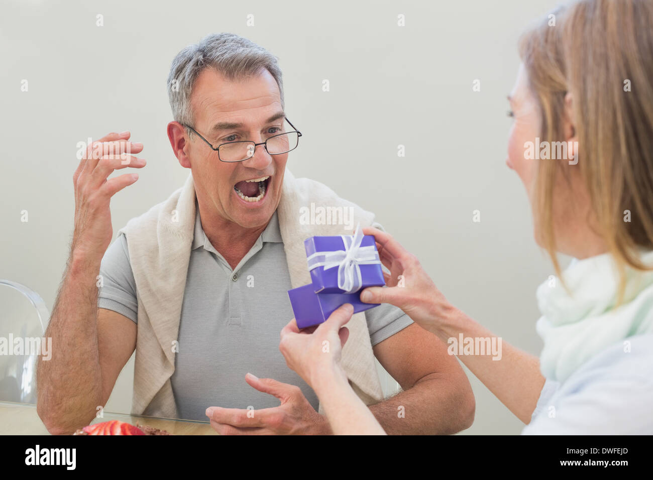 Shocked man receiving gift by woman Stock Photo - Alamy