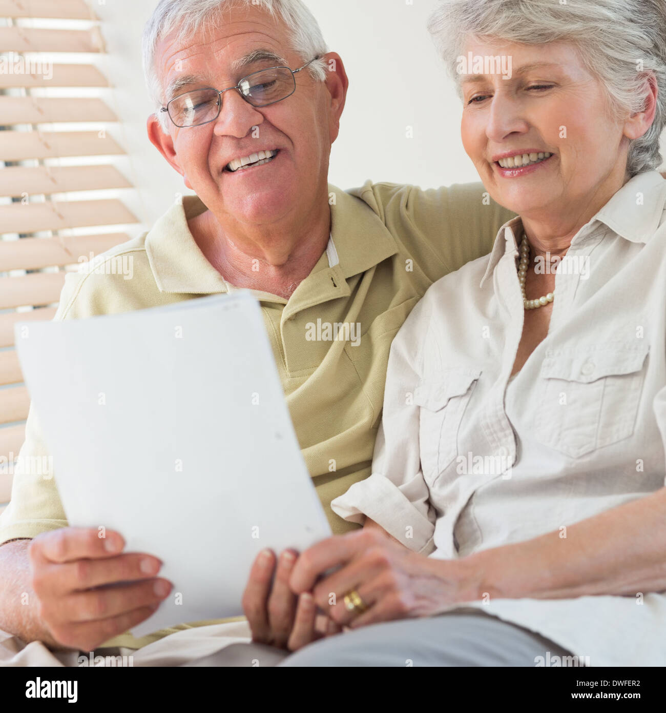 Senior couple looking at document together on the couch at home in the ...