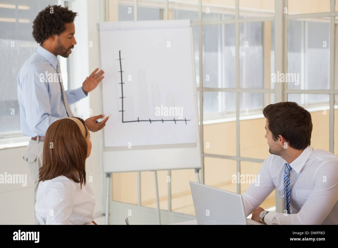 Businessman giving presentation to colleagues in office Stock Photo - Alamy