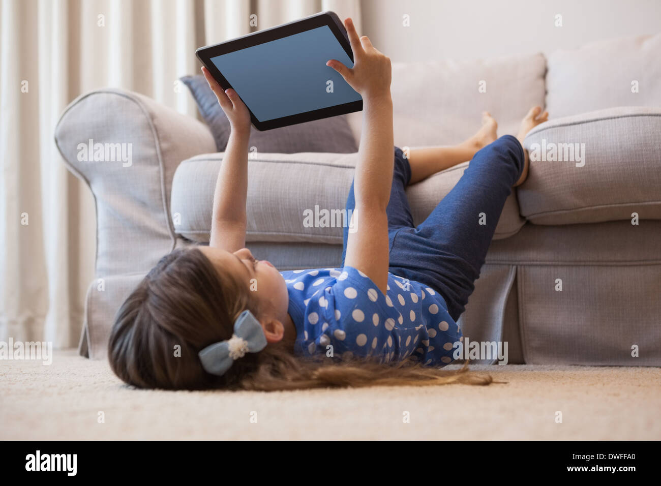 Little girl using digital tablet in the living room Stock Photo - Alamy