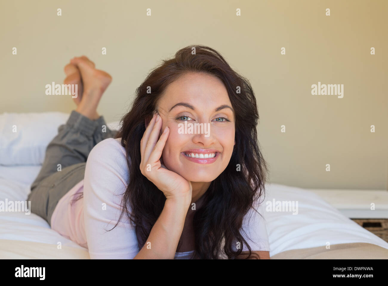 Happy woman lying in bed Stock Photo - Alamy
