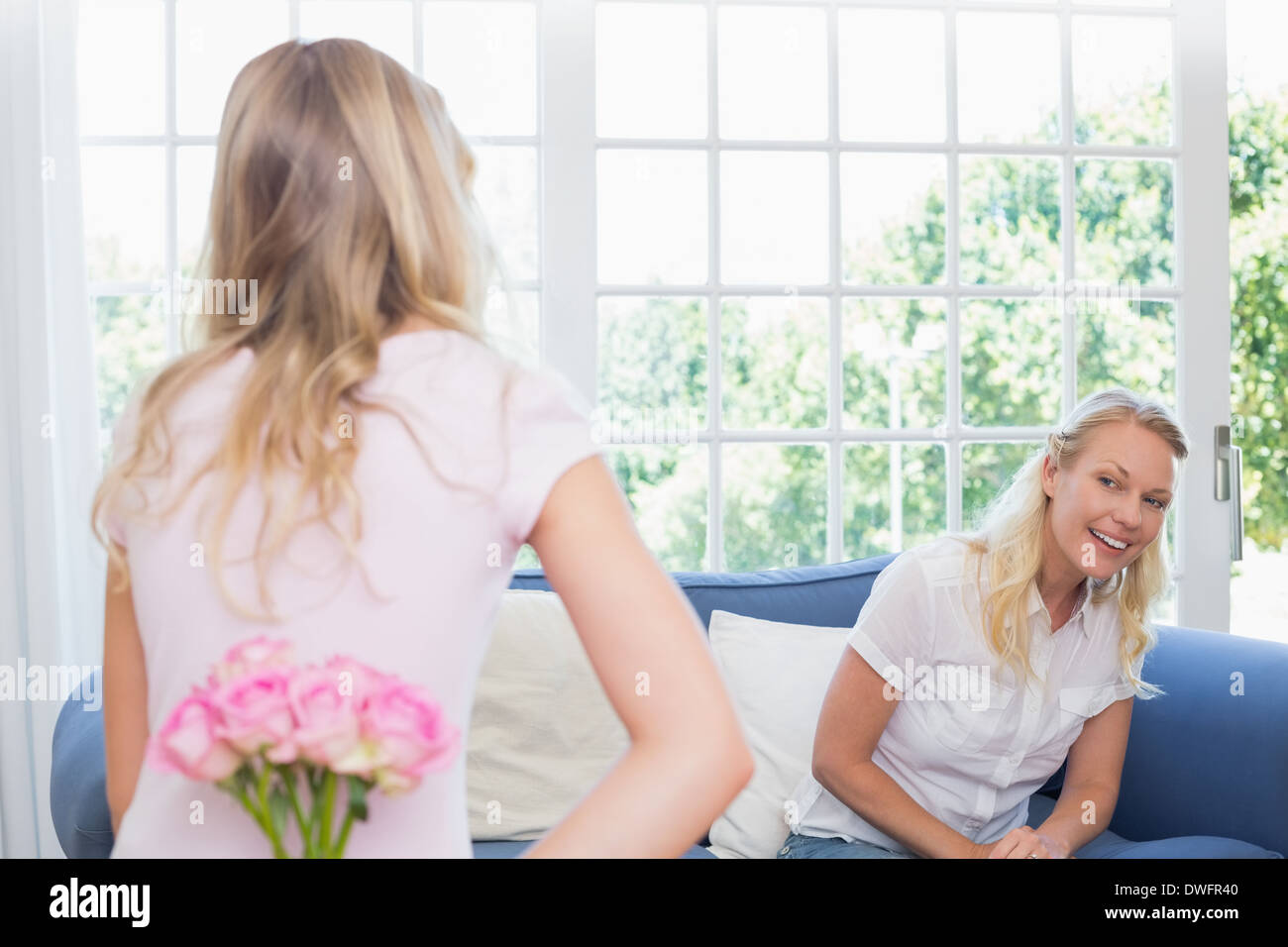Girl hiding flowers behind her back and smiling hi-res stock ...