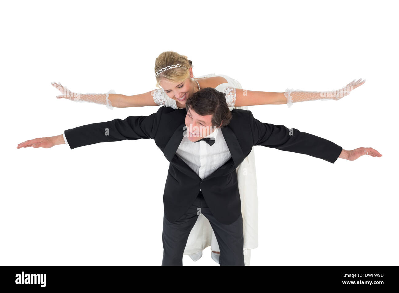 Happy groom with arms outstretched carrying bride on back Stock Photo ...