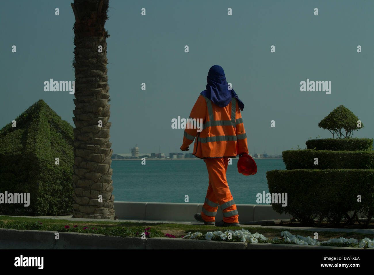 Qatar Construction worker walking along seafront topiary building site ... Qatar Construction worker walking along seafront topiary building site ...