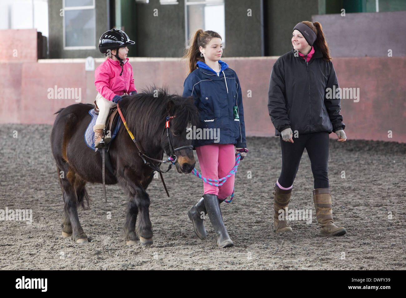 A four year old girl riding a pony during a riding lesson in North ...