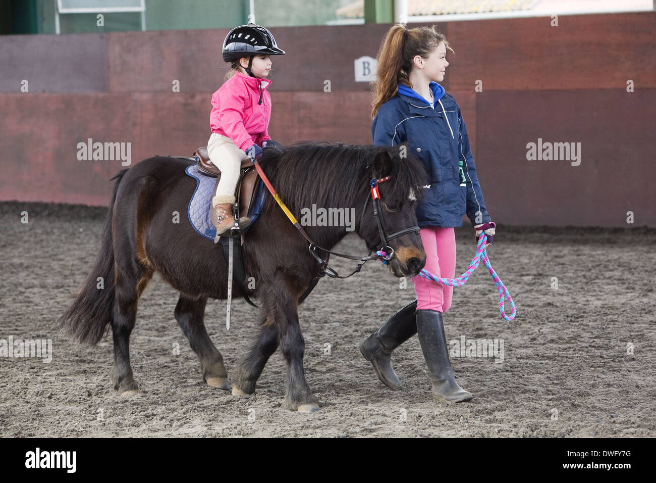 A four year old girl riding a pony during a riding lesson in North ...