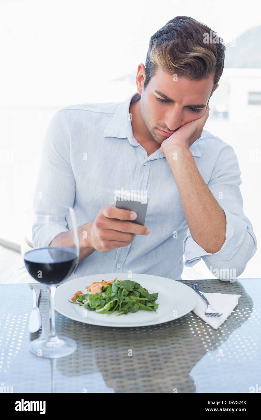 Young man text messaging at food table Stock Photo - Alamy