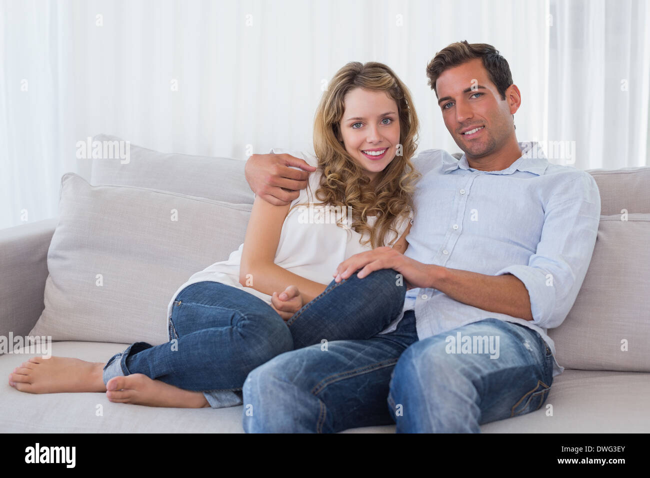 Loving young couple sitting on couch Stock Photo - Alamy