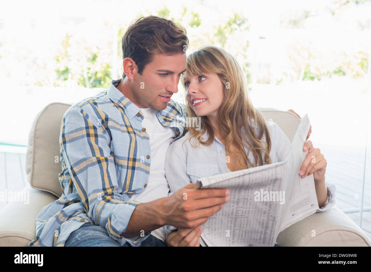 Loving happy couple reading newspaper on couch Stock Photo - Alamy