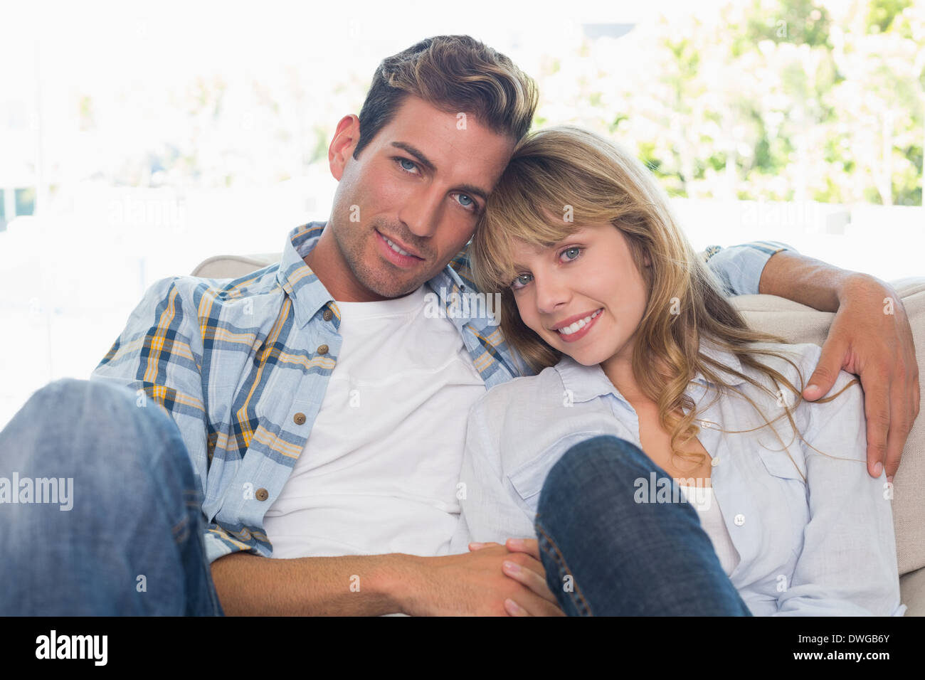 Portrait of a loving couple sitting on couch Stock Photo - Alamy