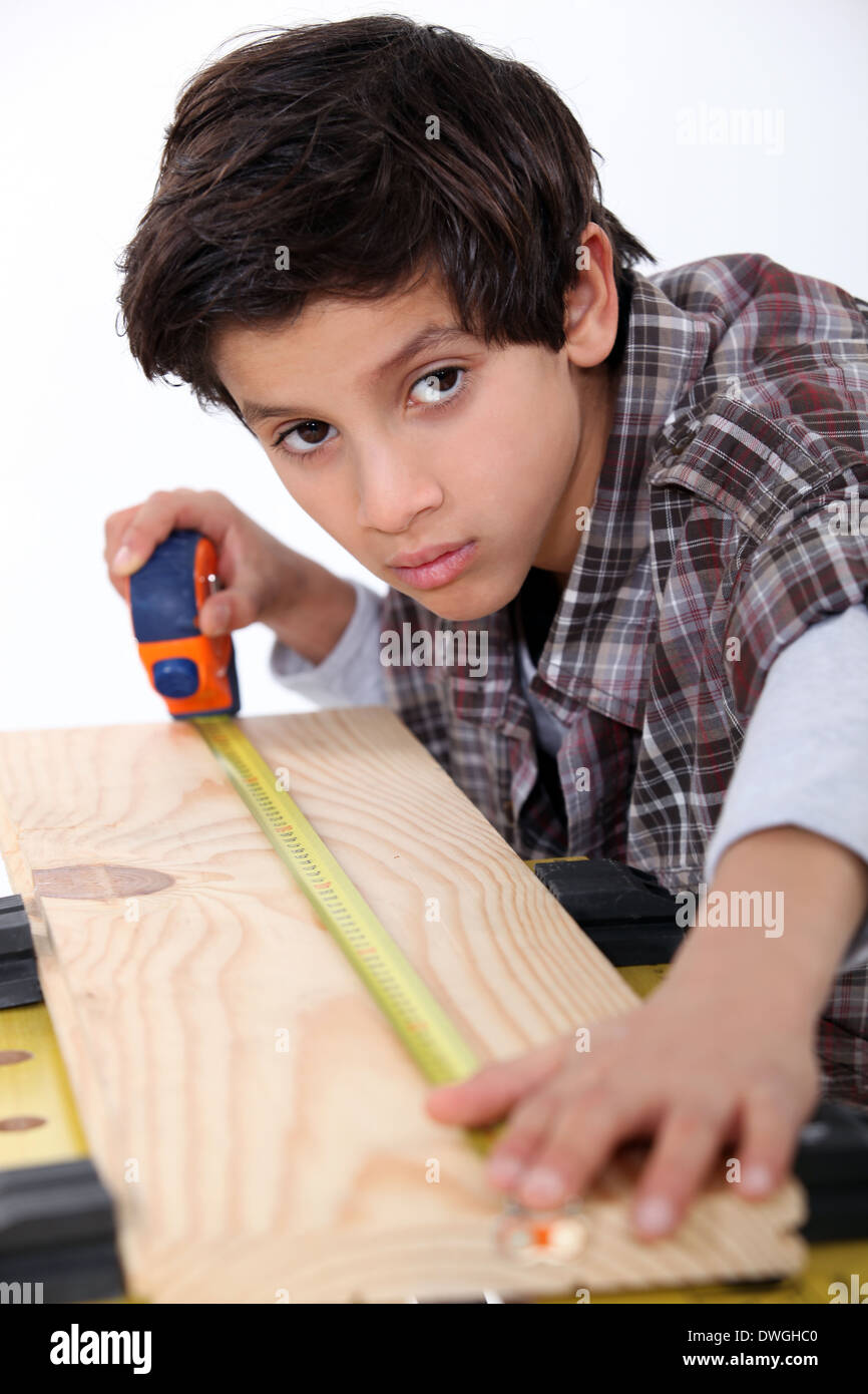 Young boy measuring a plank of wood Stock Photo - Alamy
